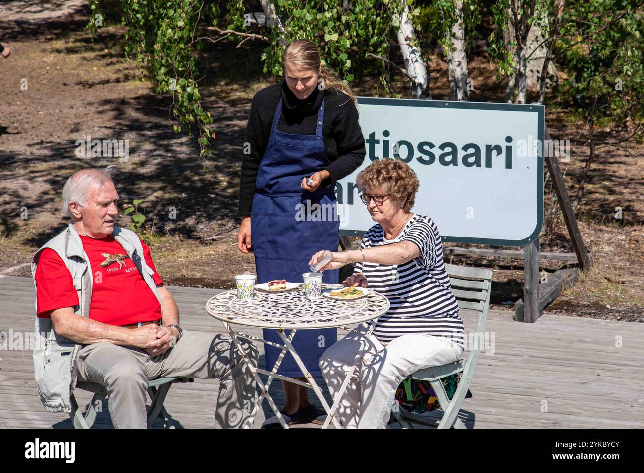 Elderly couple and waiter by outdoor cafe table on a dock in ...