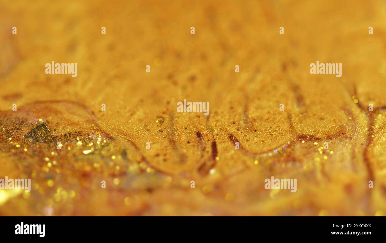 Shiny paint spill. Liquid glitter flow. Defocused golden color metallic ...