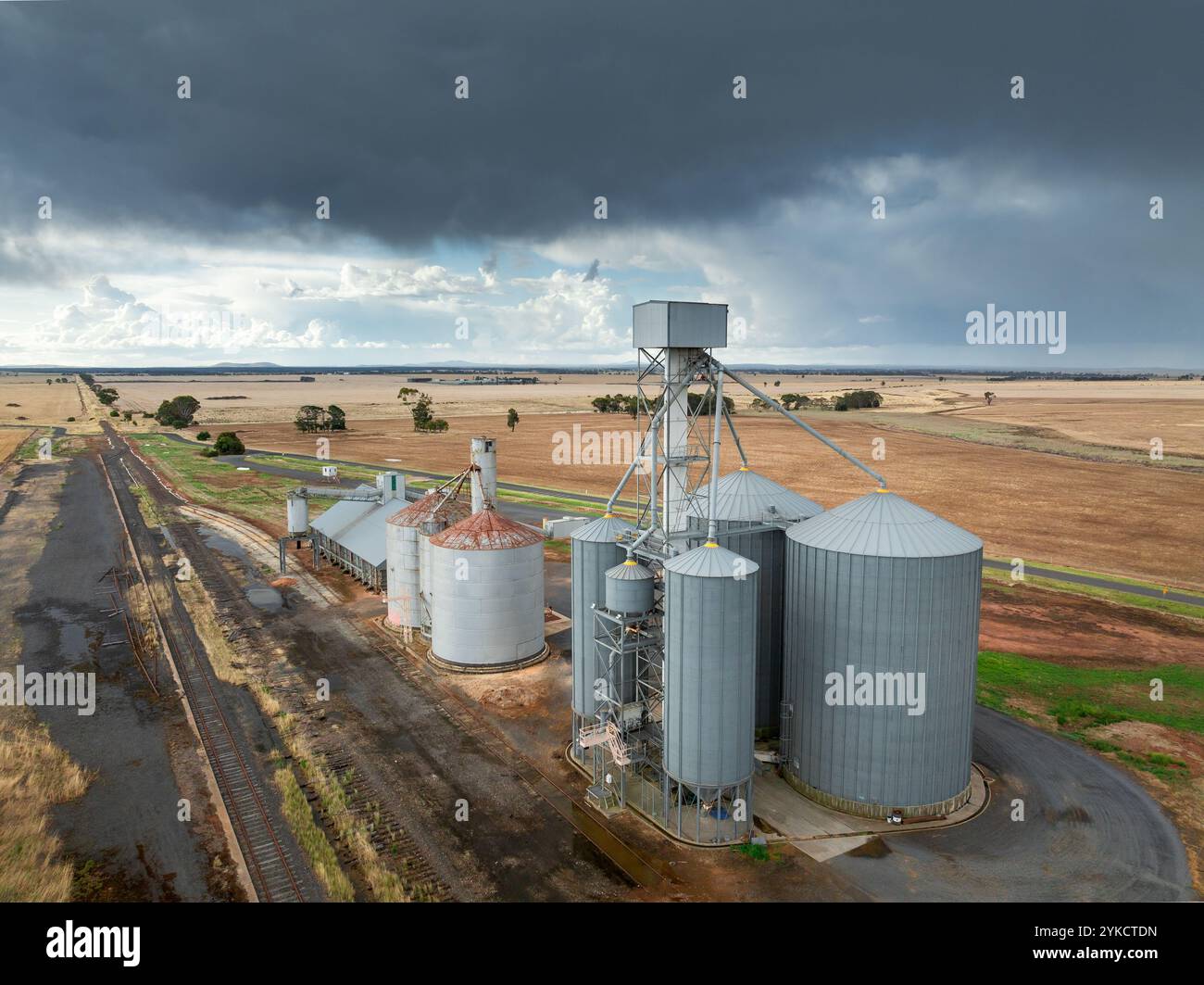 Aerial view of rain falling from dark clouds over dry farmland and ...