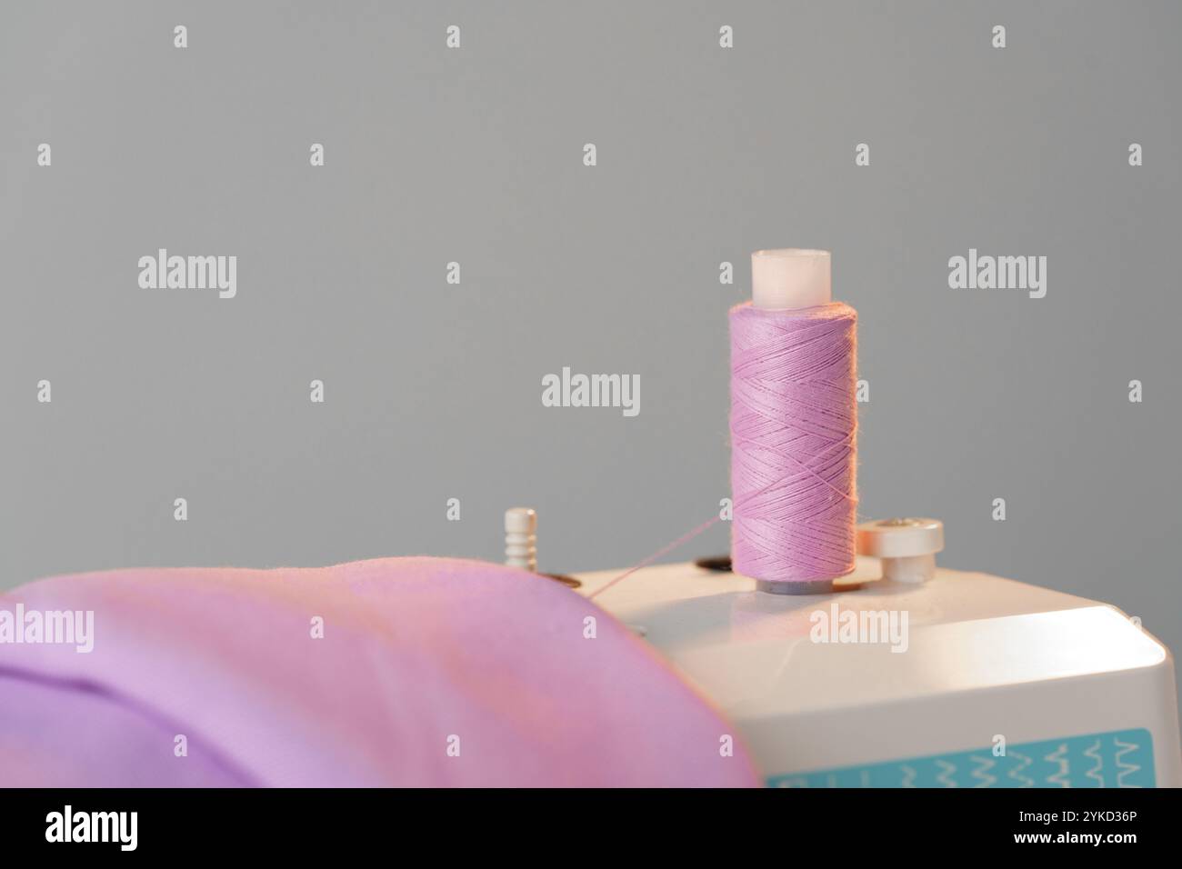View of a sewing machine with a spool of pink thread placed on top ...