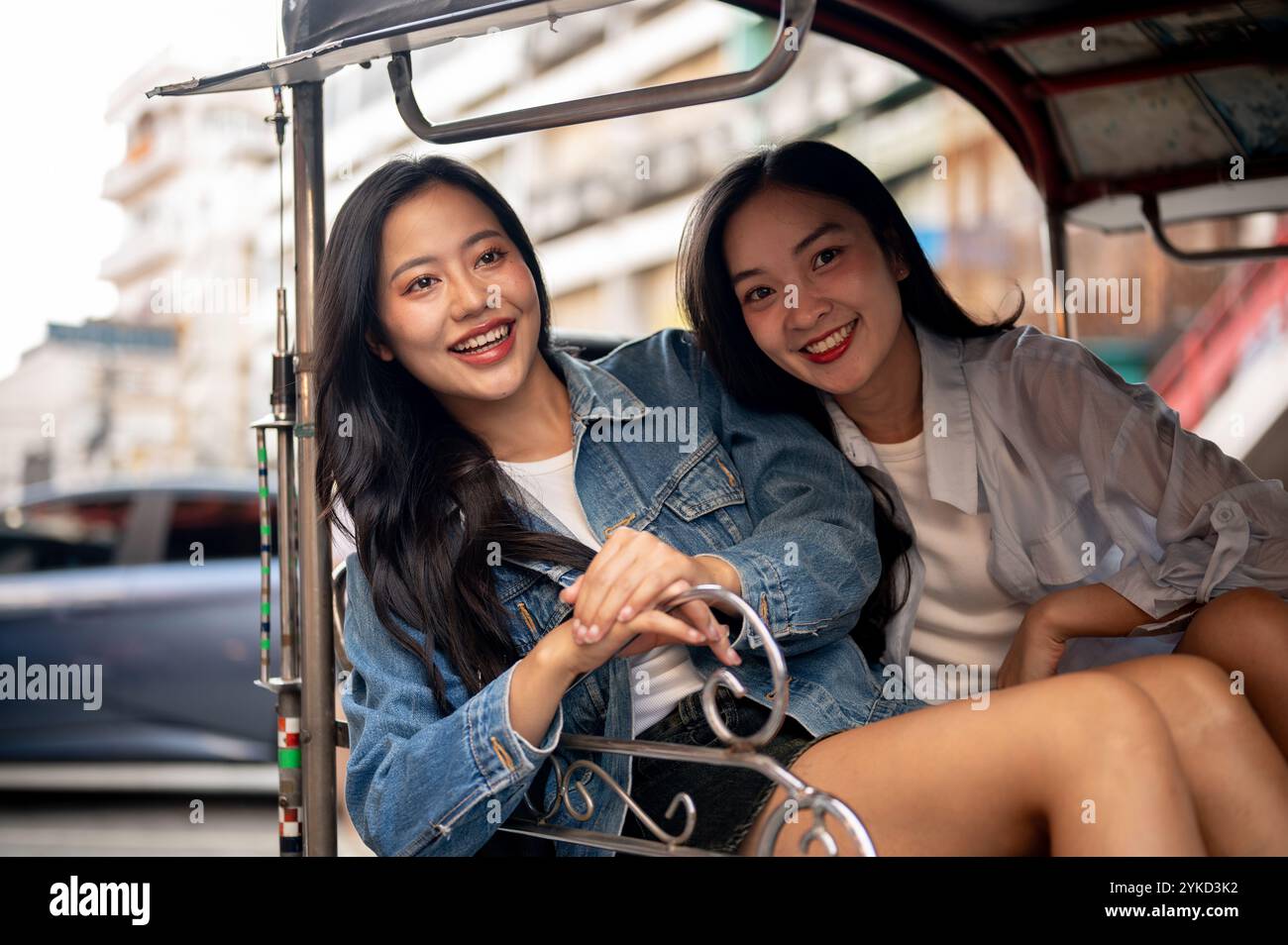 Two happy, charming young Asian girls enjoy a ride in a tuk-tuk in ...