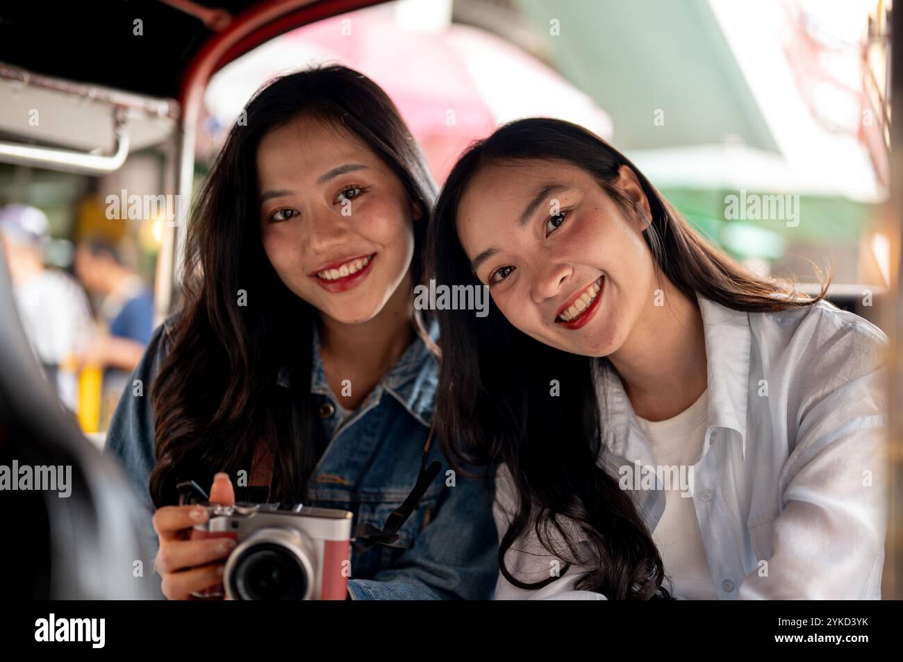 Two happy, charming young Asian girls enjoy a ride in a tuk-tuk in ...