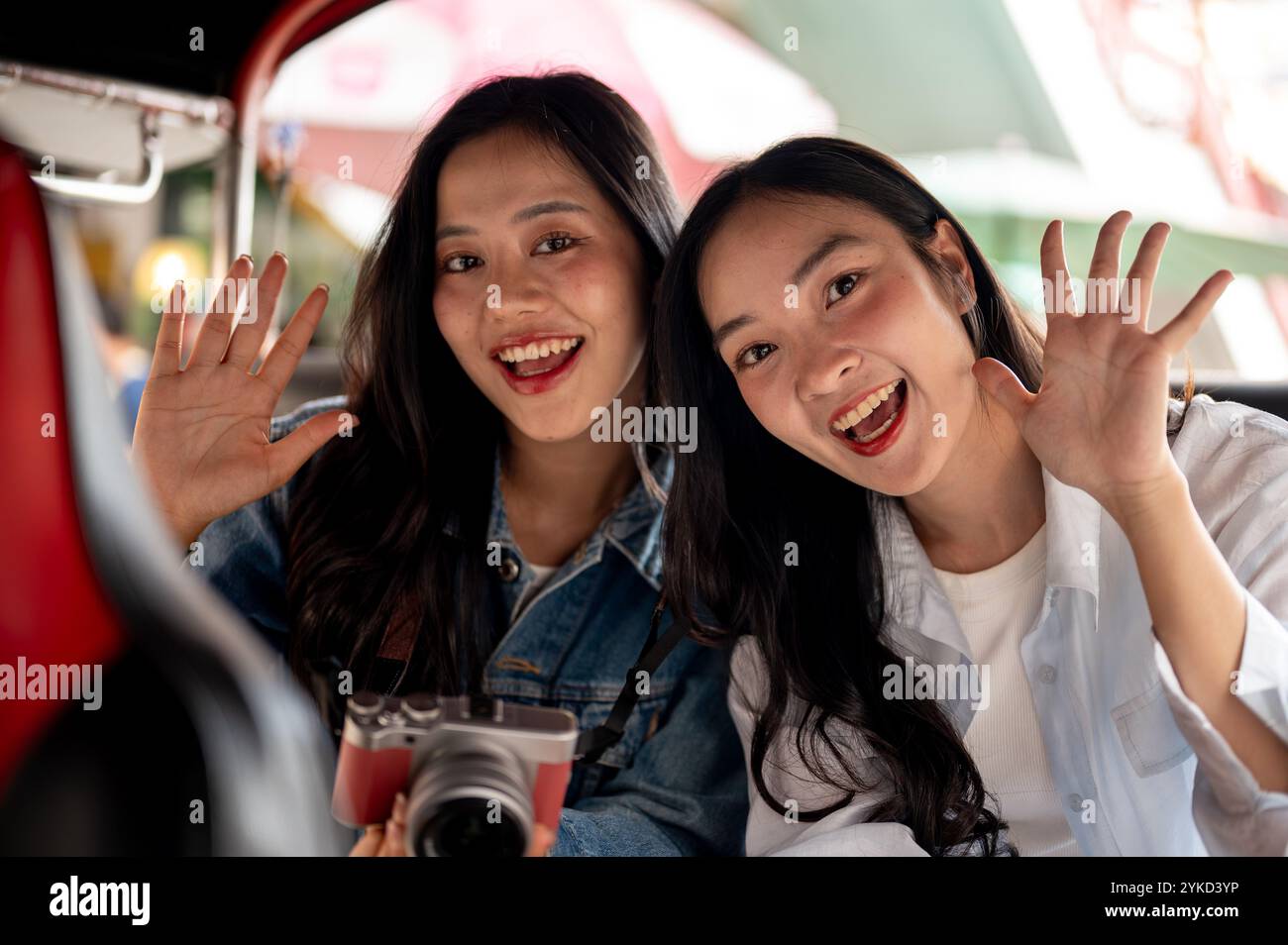 Two cheerful, charming young Asian girls enjoy a ride in a tuk-tuk in ...