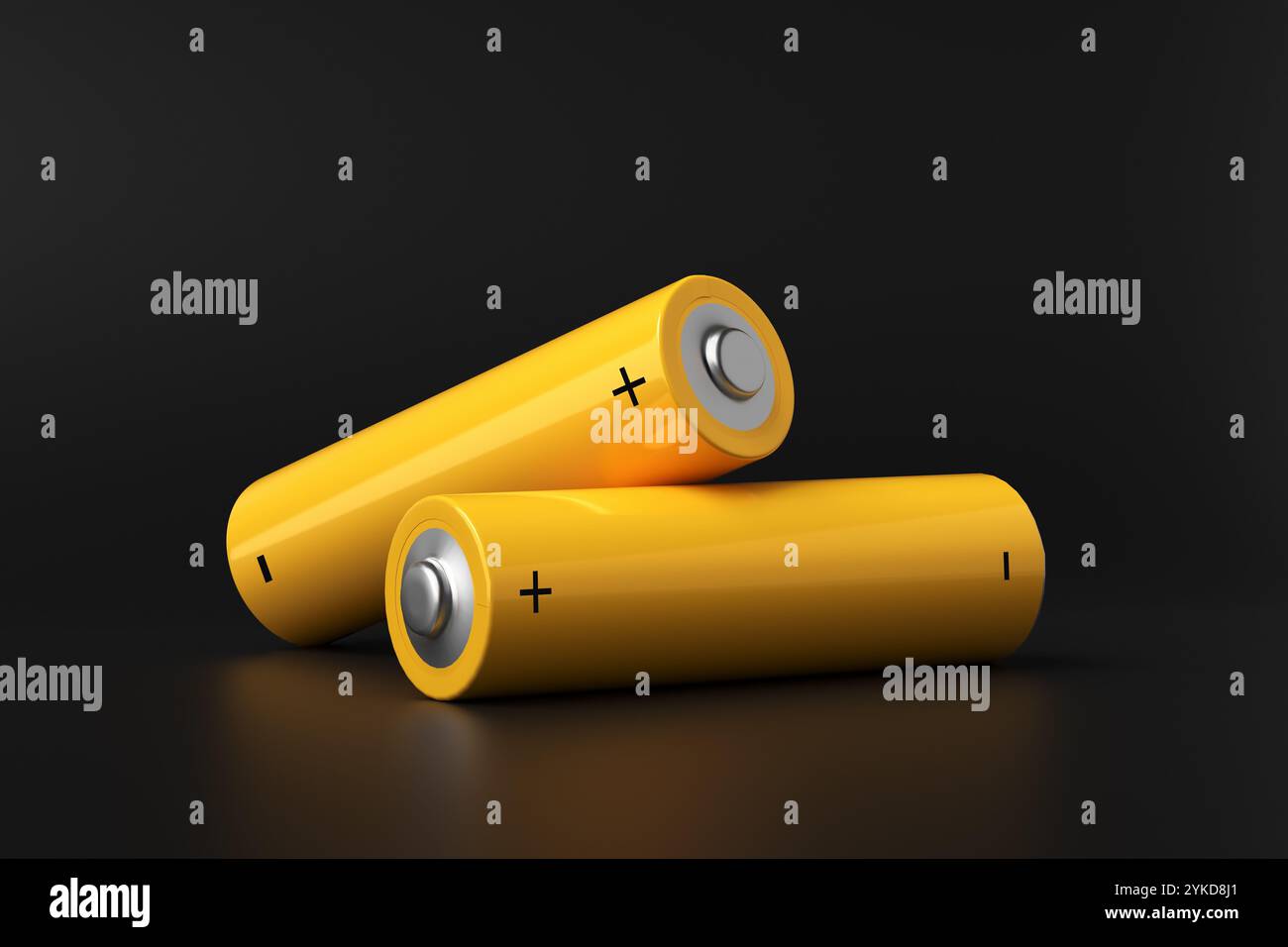 Two yellow aa batteries are lying on a dark reflective surface ...