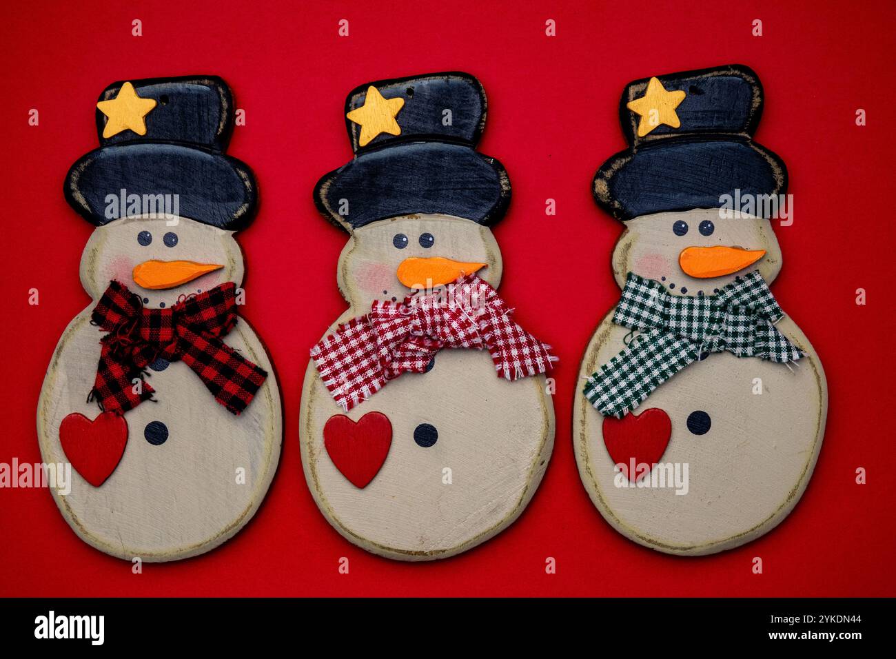 Three playful snowman figures wearing hats and scarves are arranged ...