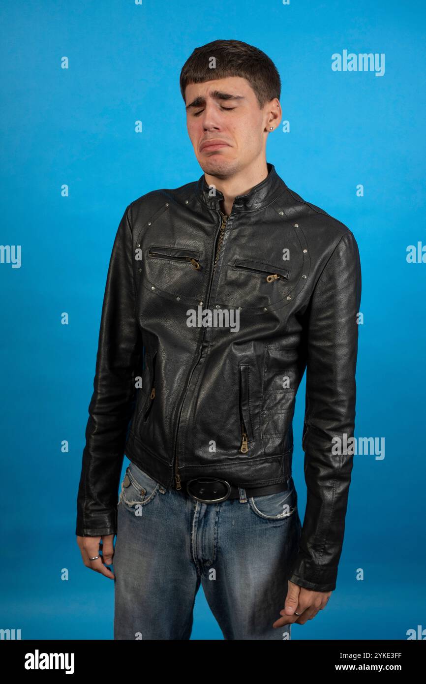 Sad young man crying because of problems, wearing black leather jacket ...