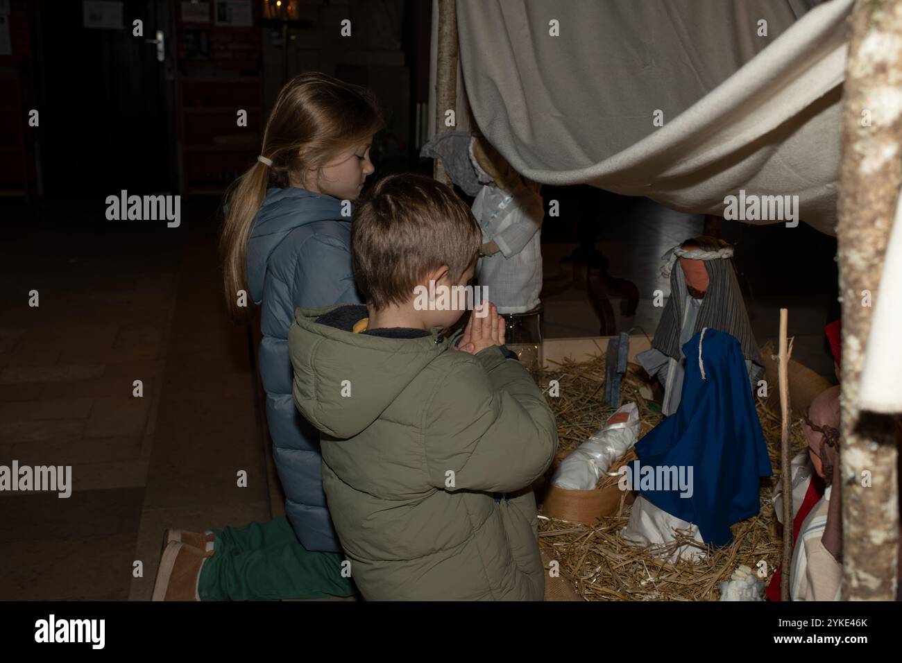 A child praying near a Christmas nativity scene with baby Jesus Creche ...