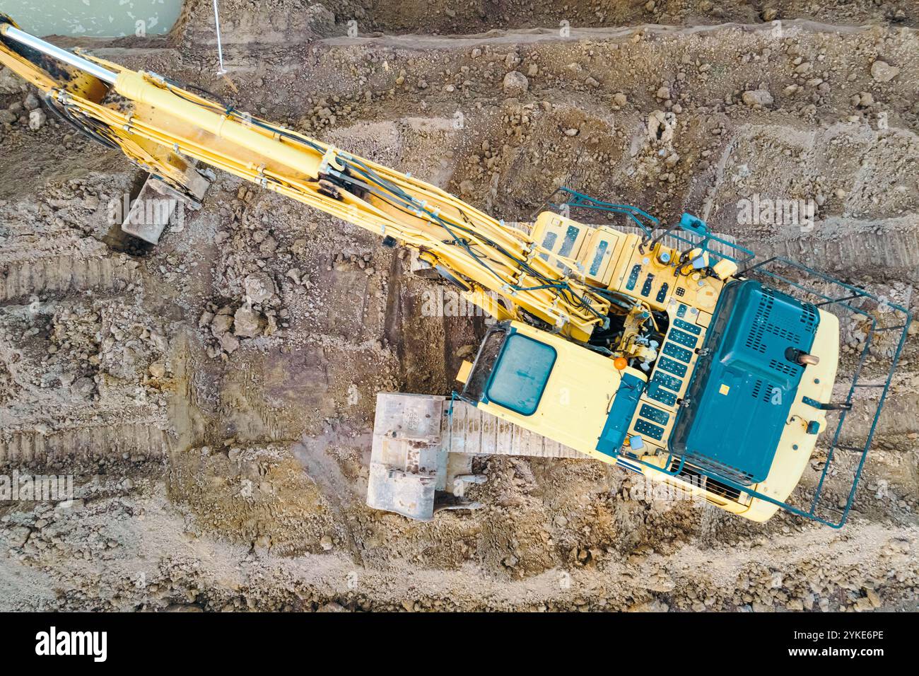 an excavator digging a trench at a construction site, top view from a ...