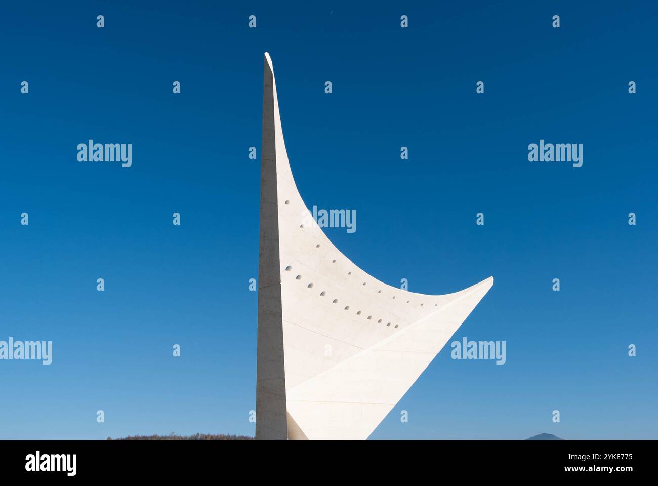 A striking white concrete monument standing tall against sunset sky ...