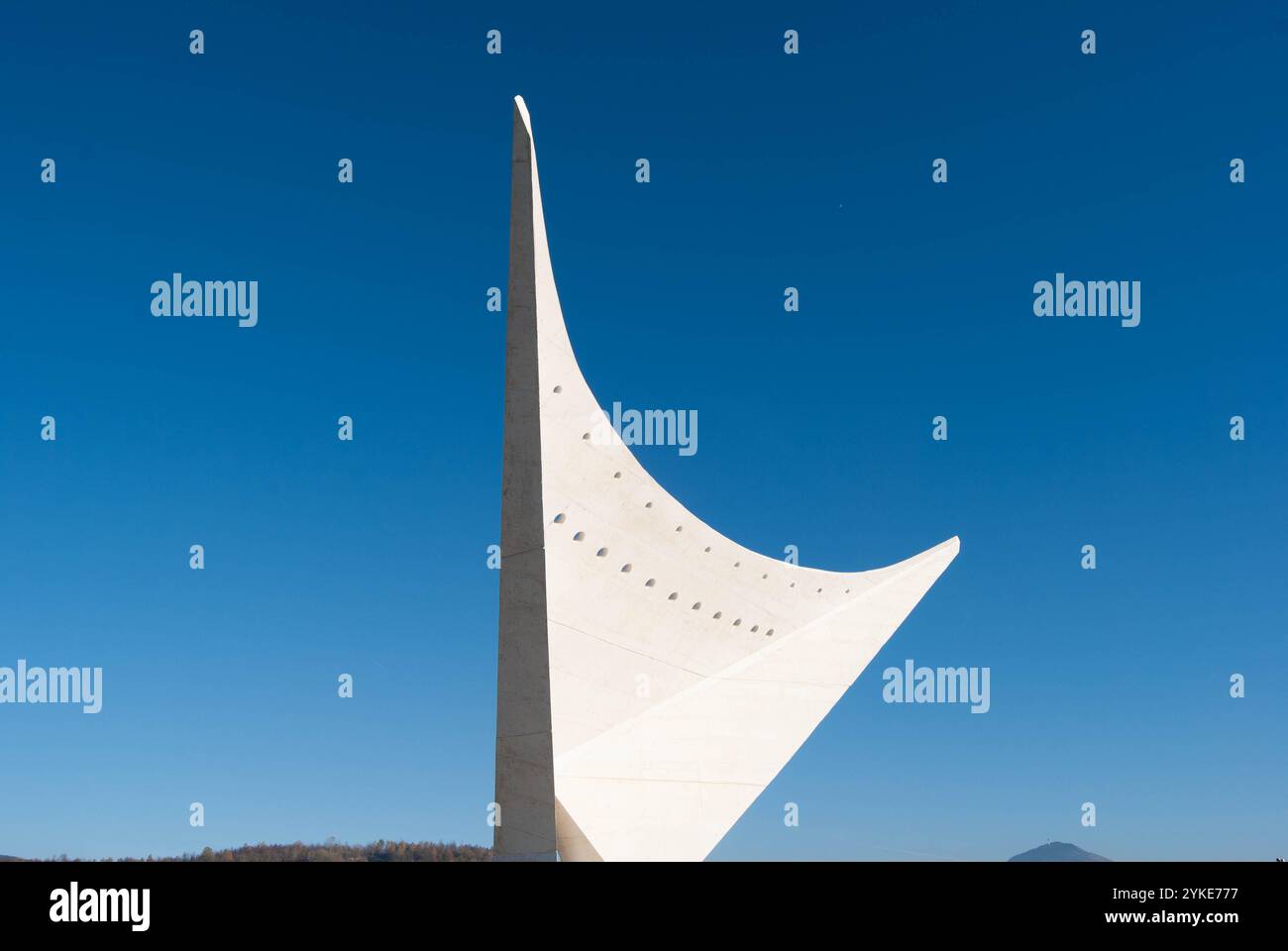 A striking white concrete monument standing tall against sunset sky ...