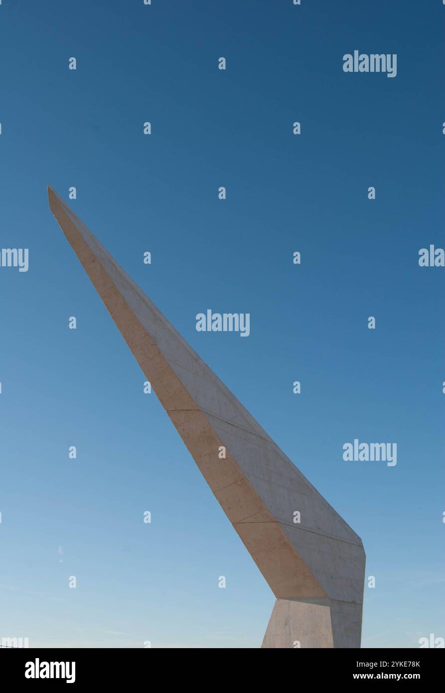 A striking white concrete monument standing tall against a bright blue ...