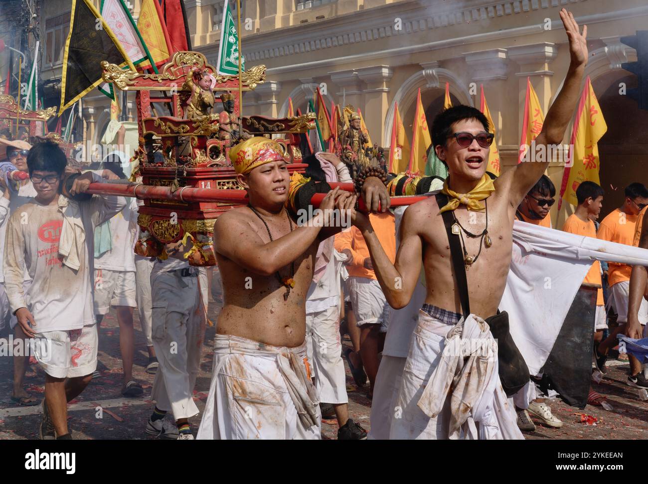 Young Thai men carrying palanquins with figures of Chinese gods during ...