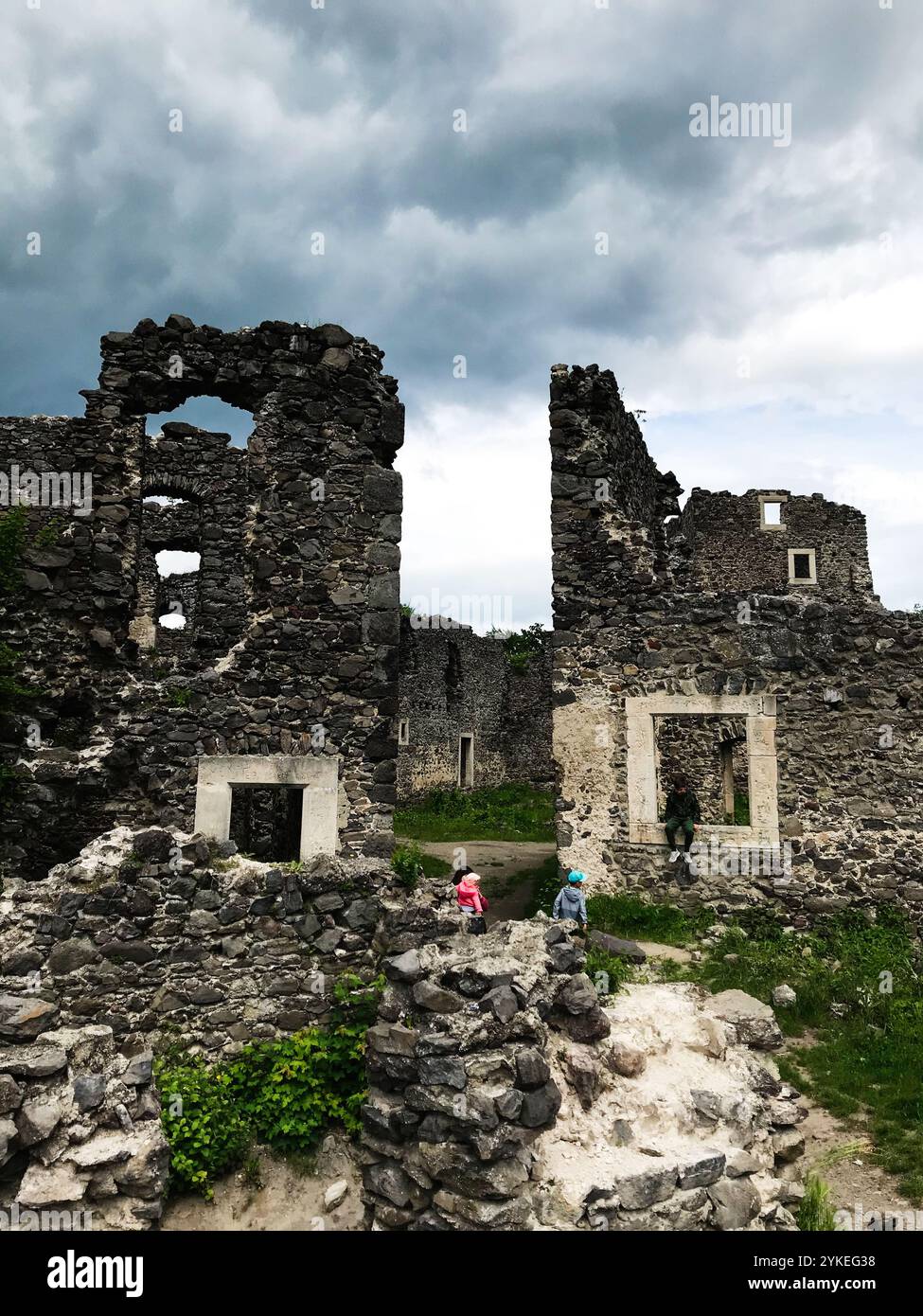 Two children wander through ancient stone ruins, with dramatic clouds ...