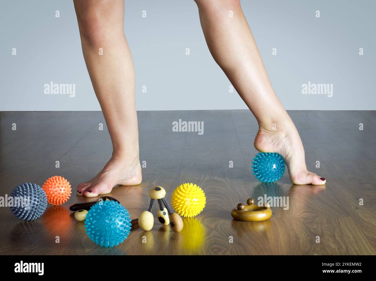 ballet dancer massaging her foot with blue ball for massage, wooden ...