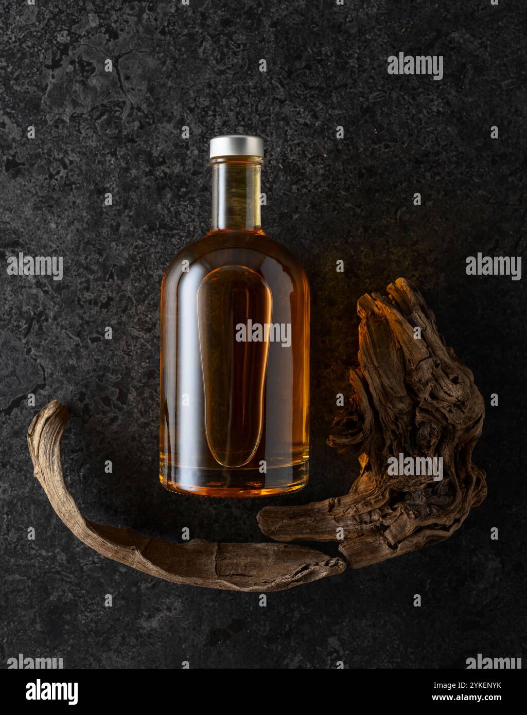 Bottle of whiskey and old snags on a black stone background. Top view ...