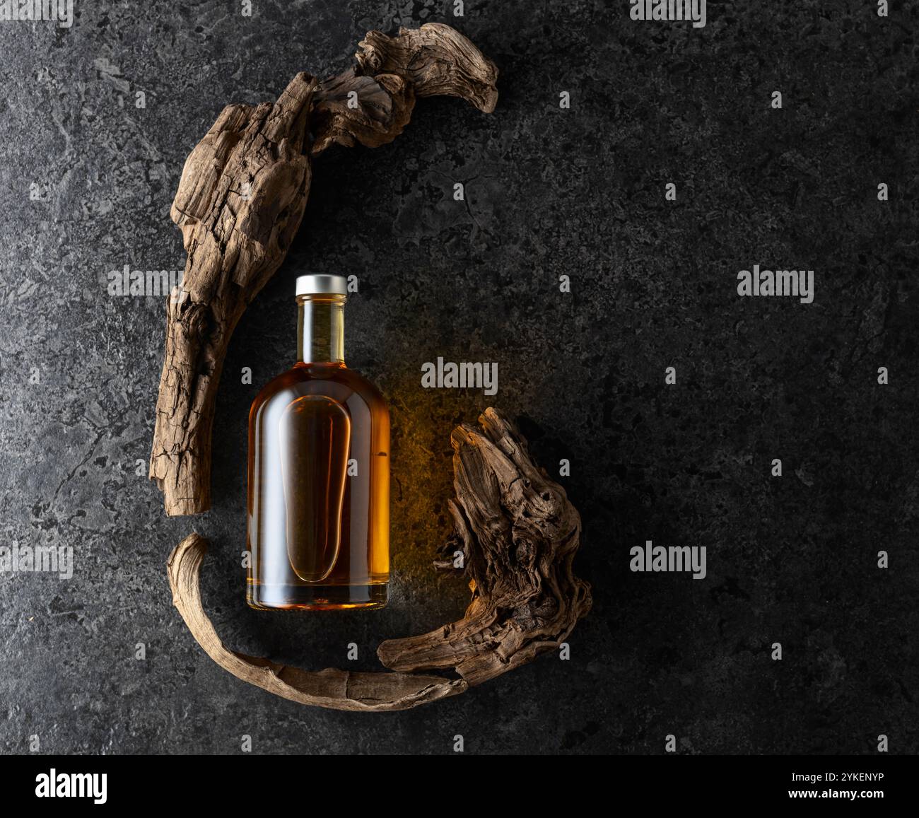 Bottle of whiskey and old snags on a black stone background. Top view ...