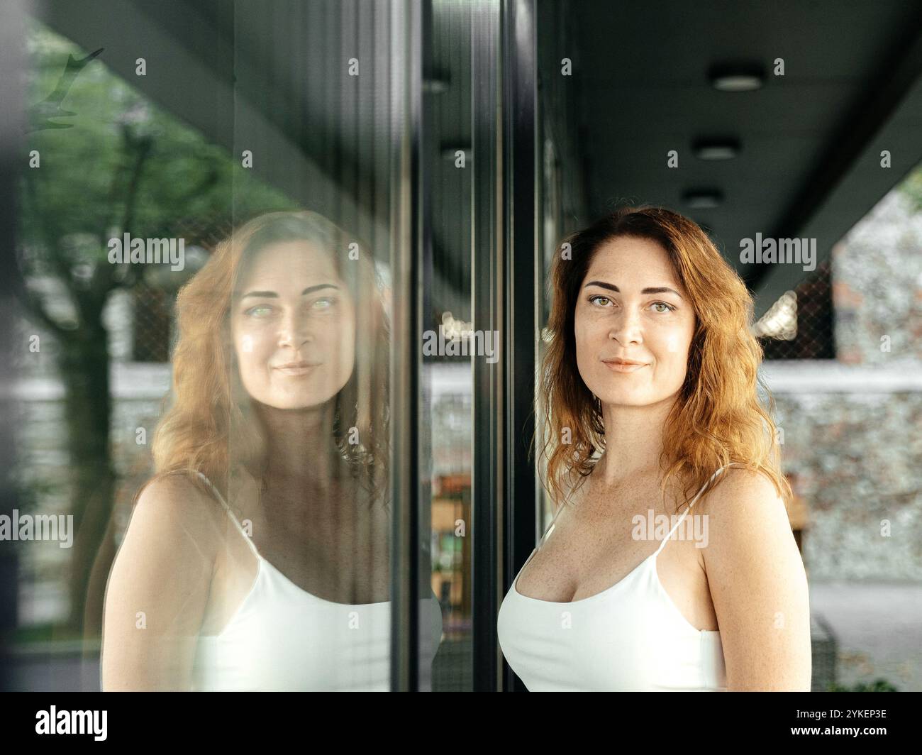 Woman gazing through a reflective glass wall with expression Stock ...