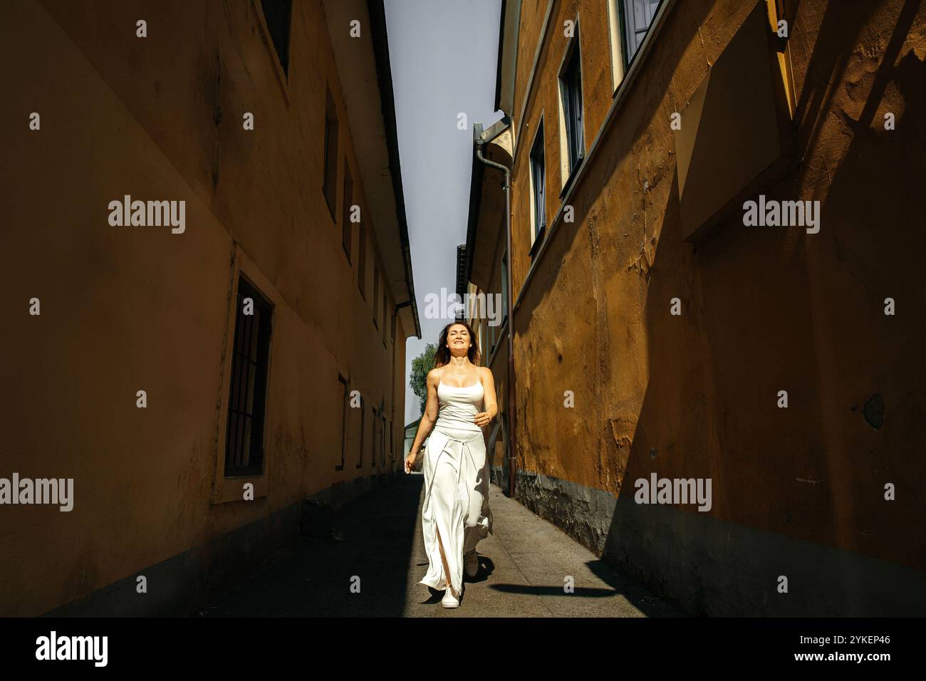 Woman walking confidently down narrow alleyway Stock Photo - Alamy
