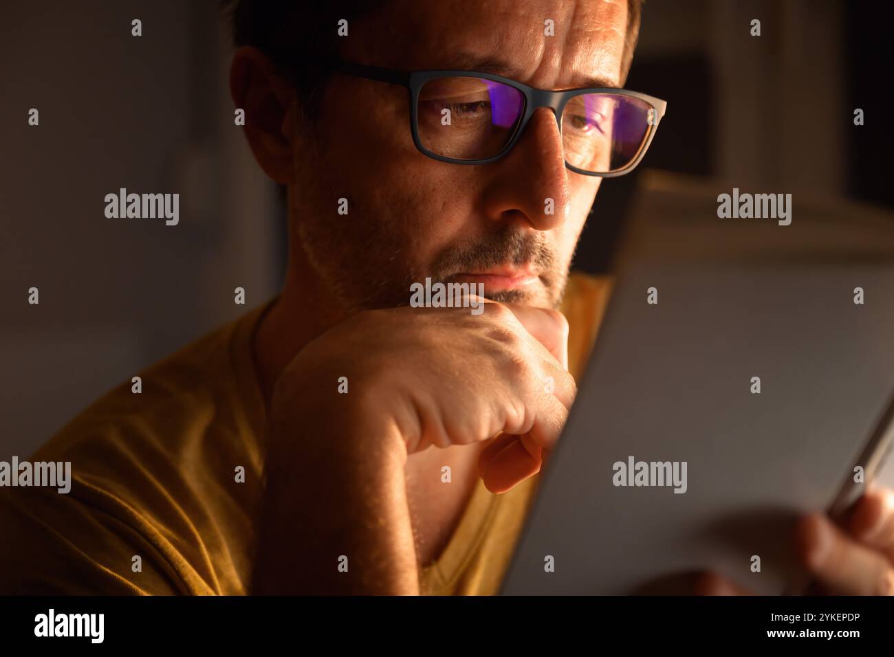 Bookworm reading literature book at night in dark room, his face is lit ...