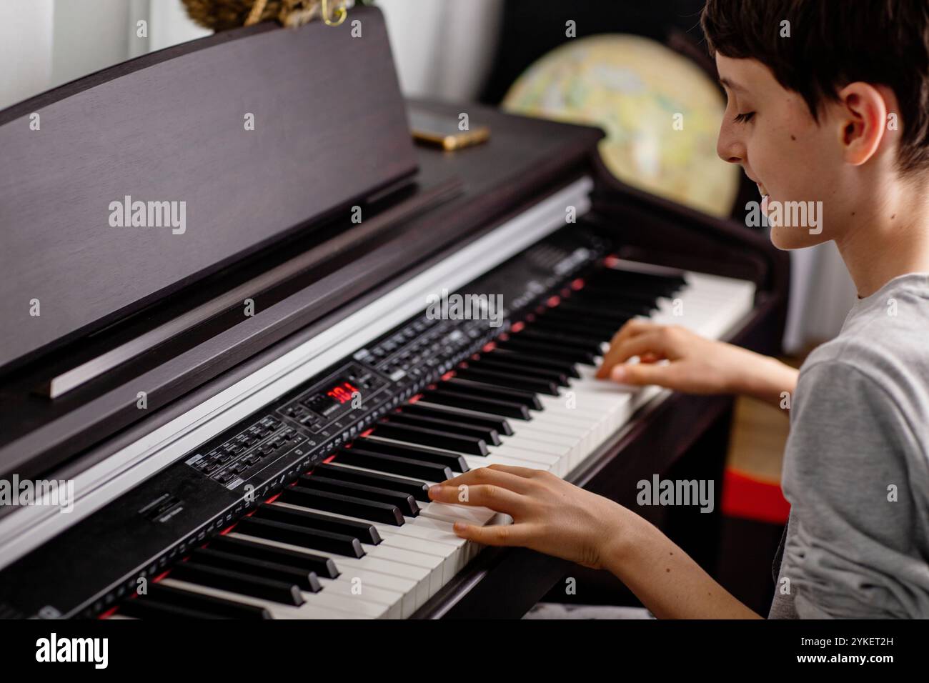 Side view of smiling boy playing piano at home Stock Photo - Alamy