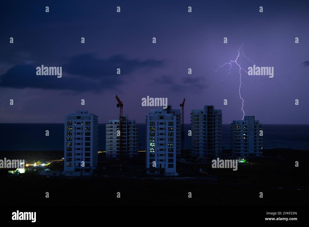 A dramatic lightning bolt illuminates the night sky above towering ...