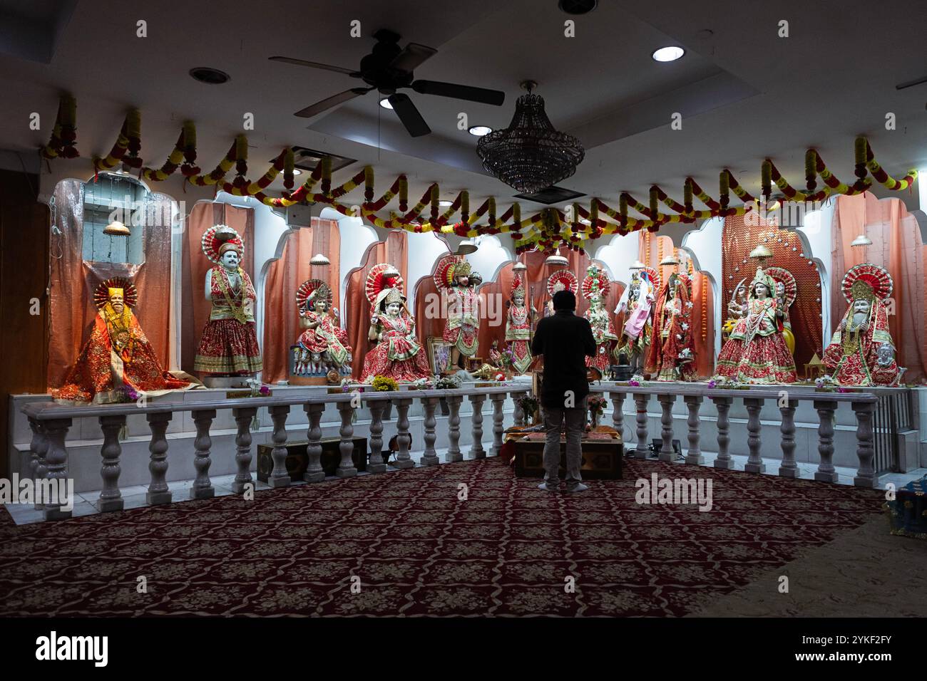 An anonymous Hindu man prays and meditates in front of statues of ...