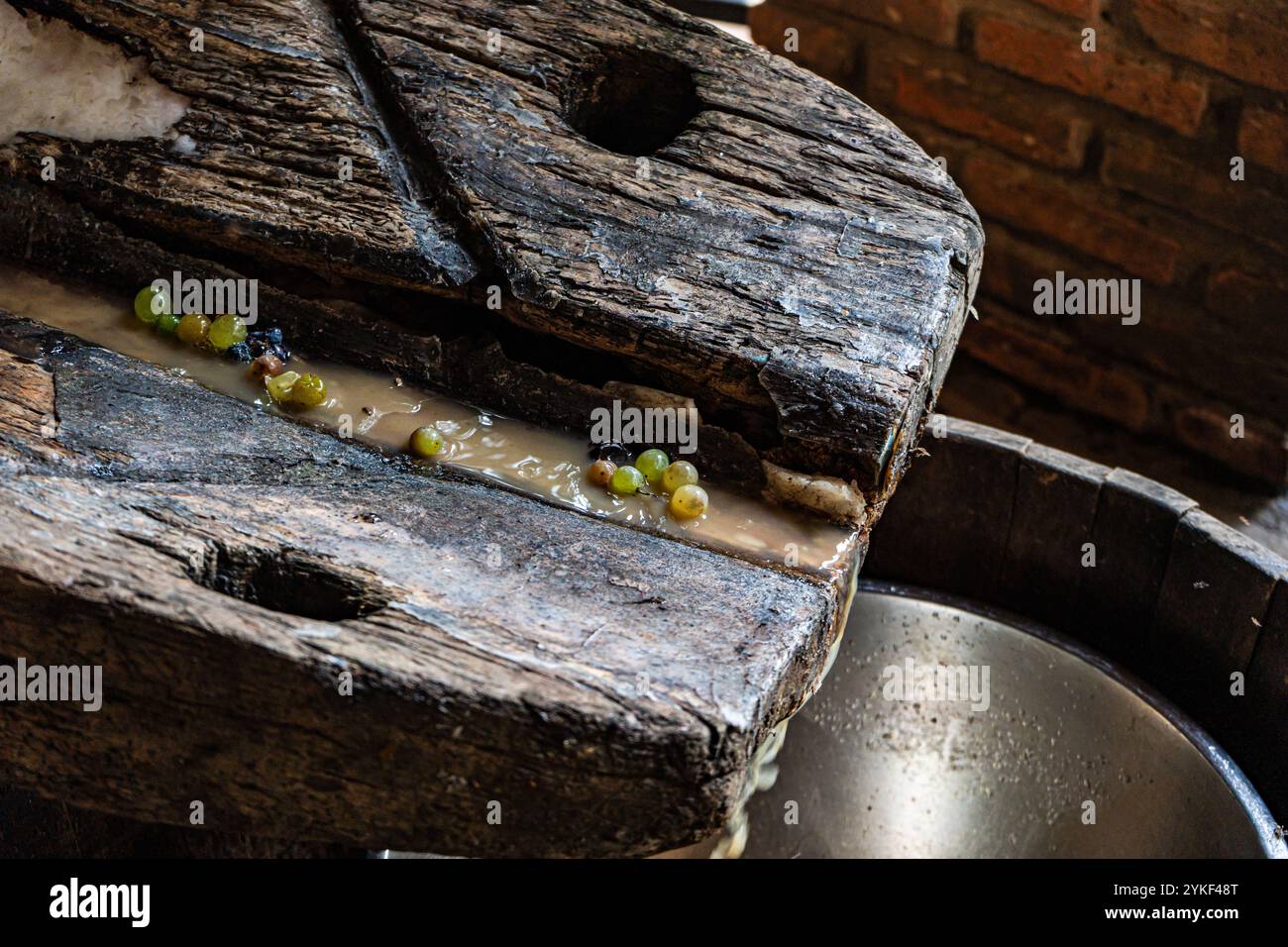 A close-up of a rustic wooden grape press used in traditional ...