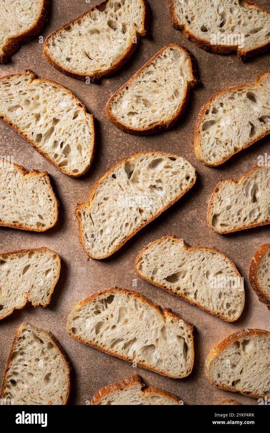 Rustic artisan bread slices arranged on a textured brown background The ...