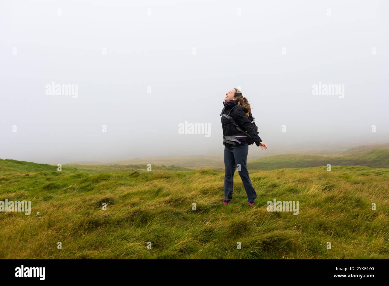 Cheerful young female exploring nature outdoors in misty cold weather ...