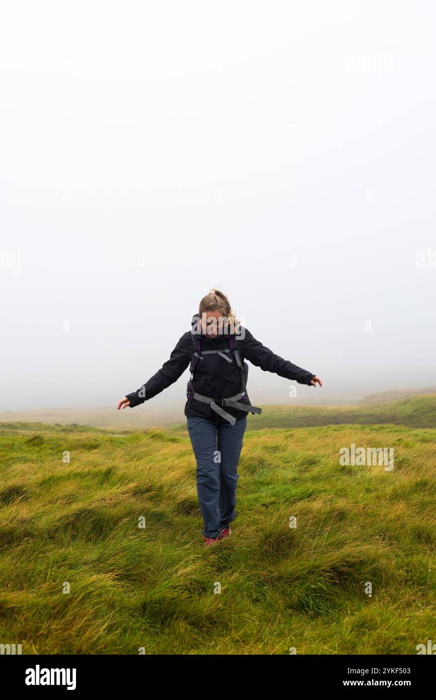 Cheerful young female exploring nature outdoors in misty cold weather ...