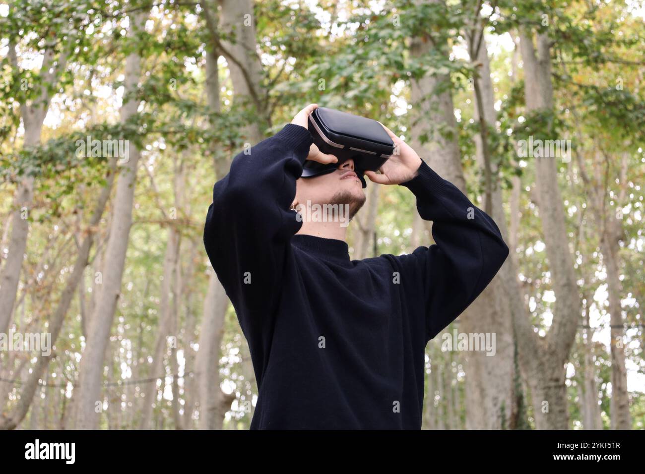 A young trans man dressed in a black sweater uses a virtual reality ...