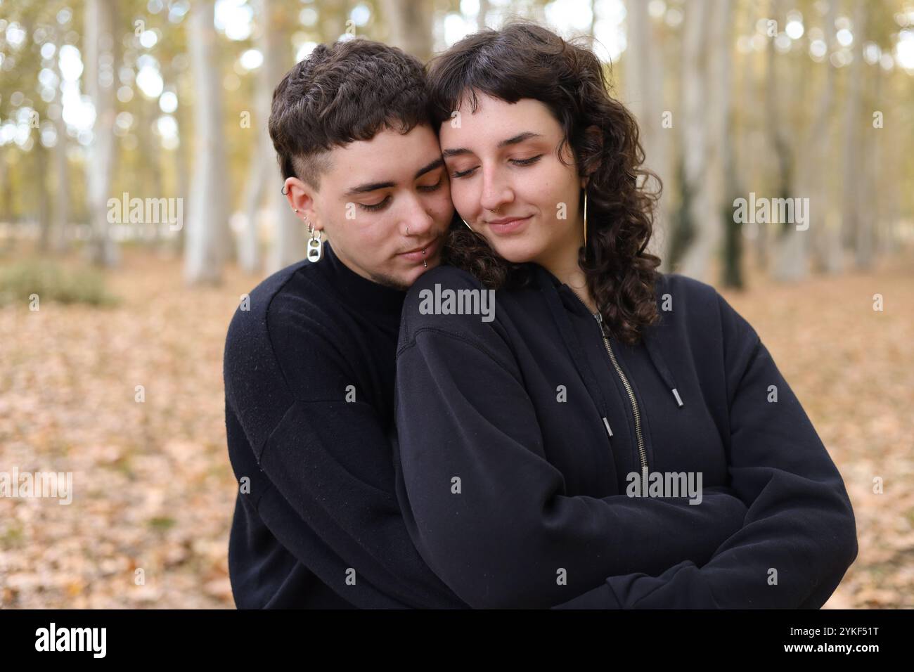 LGBTQIA+ couple shares a tender embrace surrounded by autumn leaves ...