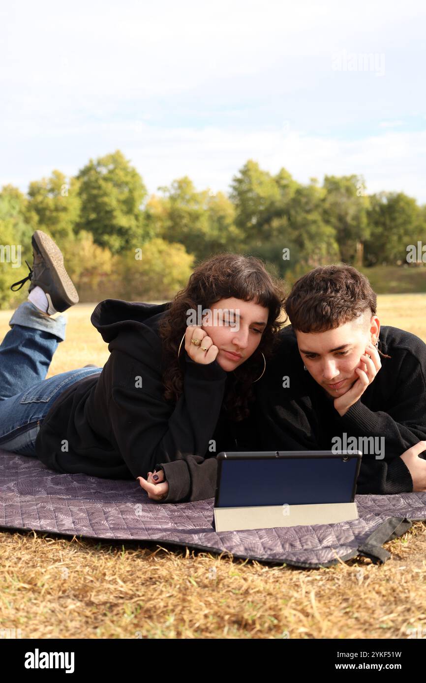 An LGBTQIA+ couple, featuring a trans man, lounges on a blanket ...