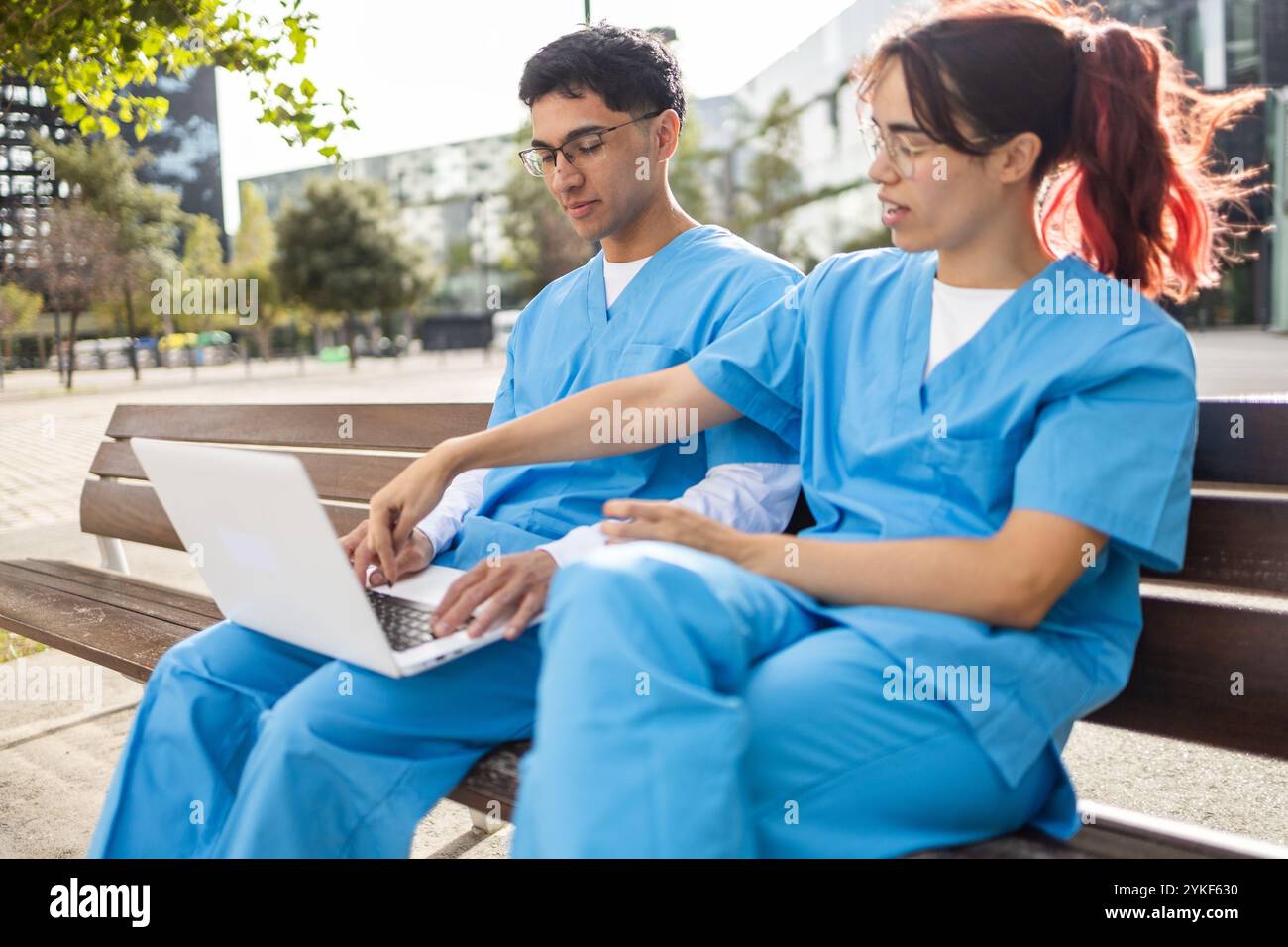 Two nurse students, dressed in blue scrubs, are engaged in discussion ...