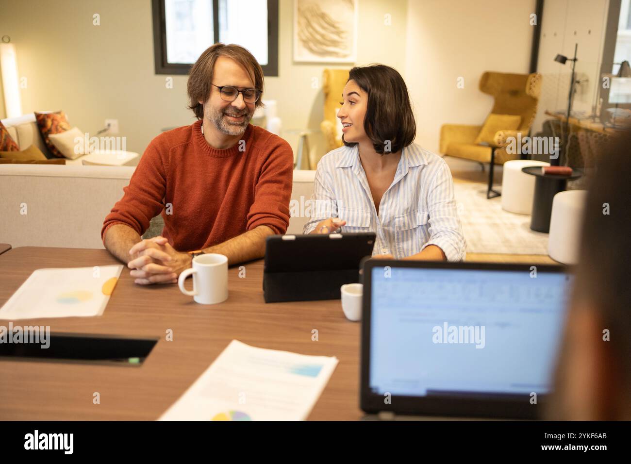 Two colleagues engage in a lively discussion over coffee in a stylish ...