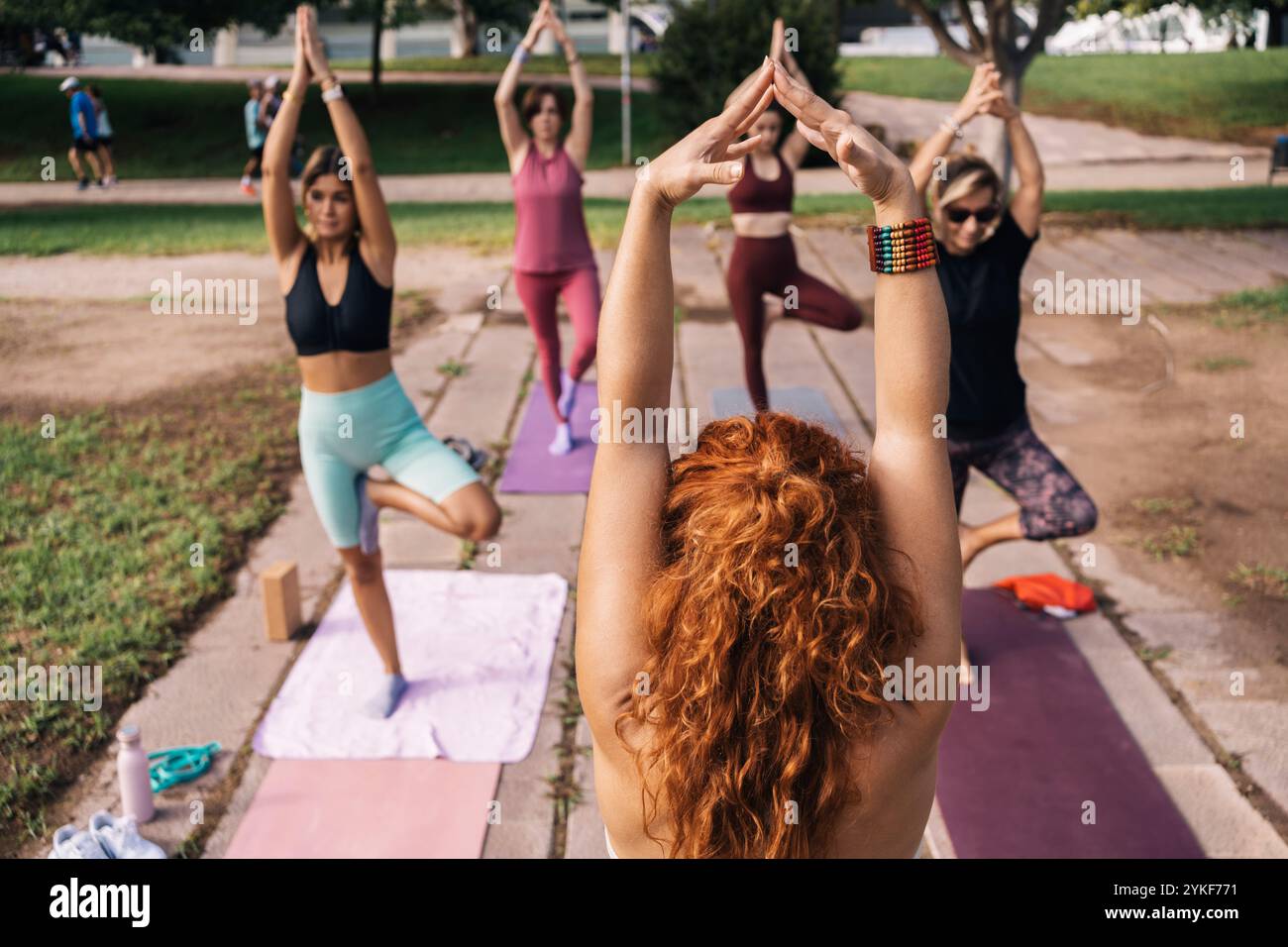 Multiple women participate in an outdoor yoga session, practicing the ...