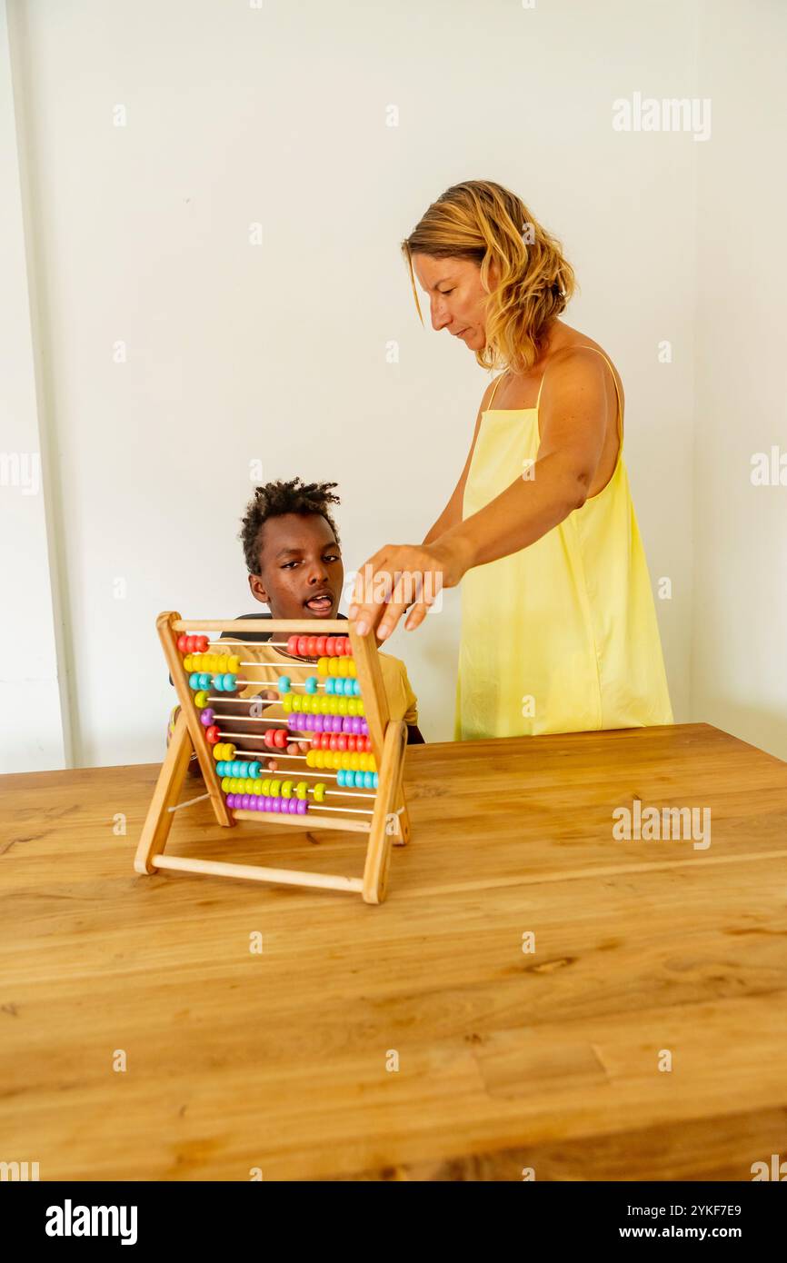 An African American boy with curly hair and his female teacher using an ...