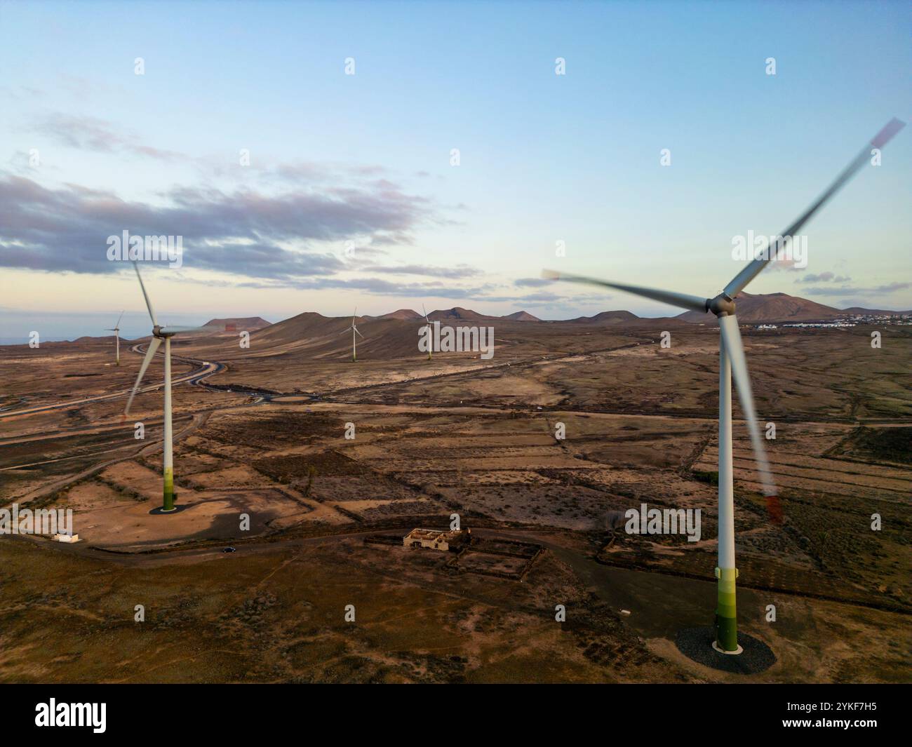 Aerial view of wind turbines spinning in a wide, dry landscape as the ...