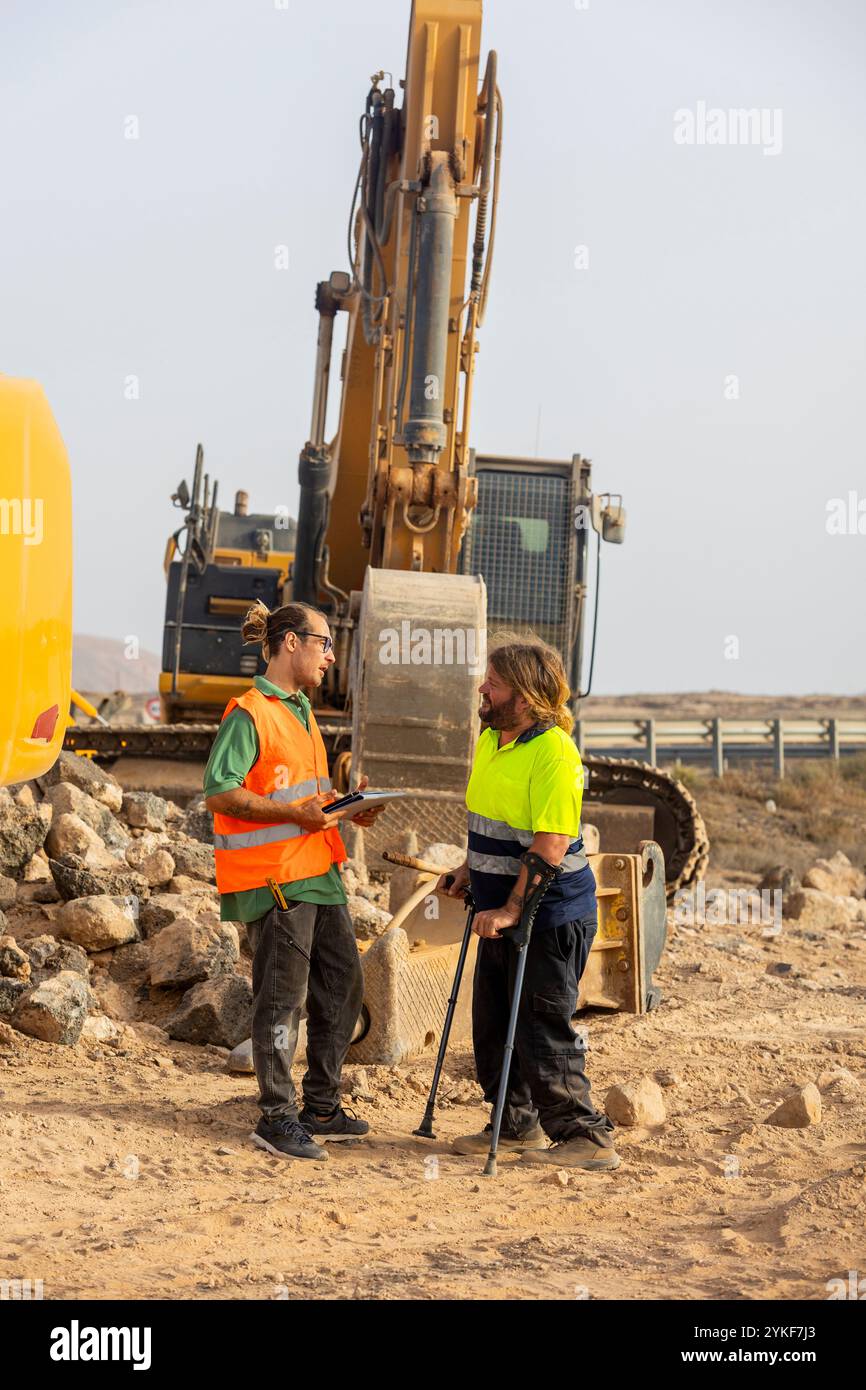 A disabled inspector on crutches and his colleague, both wearing ...