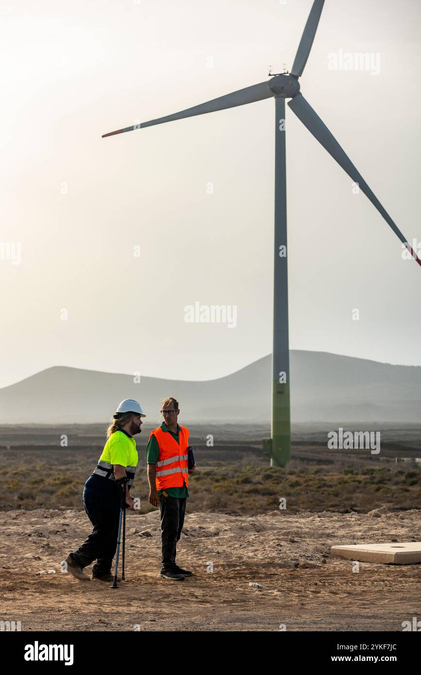 A disabled inspector using crutches discusses with a colleague in front ...