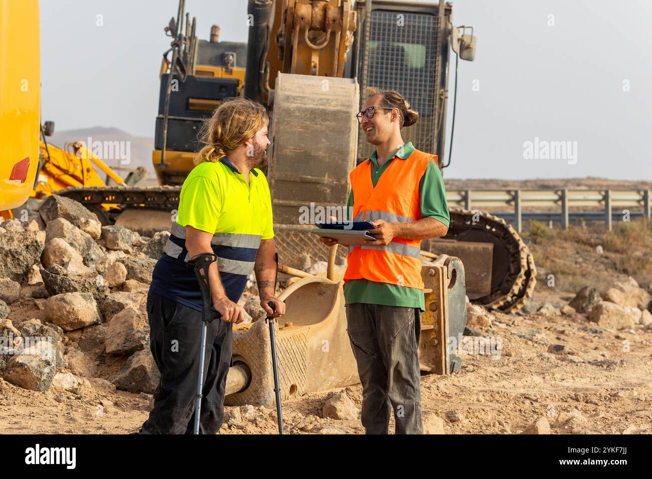 A disabled inspector using crutches converses with a colleague at a ...