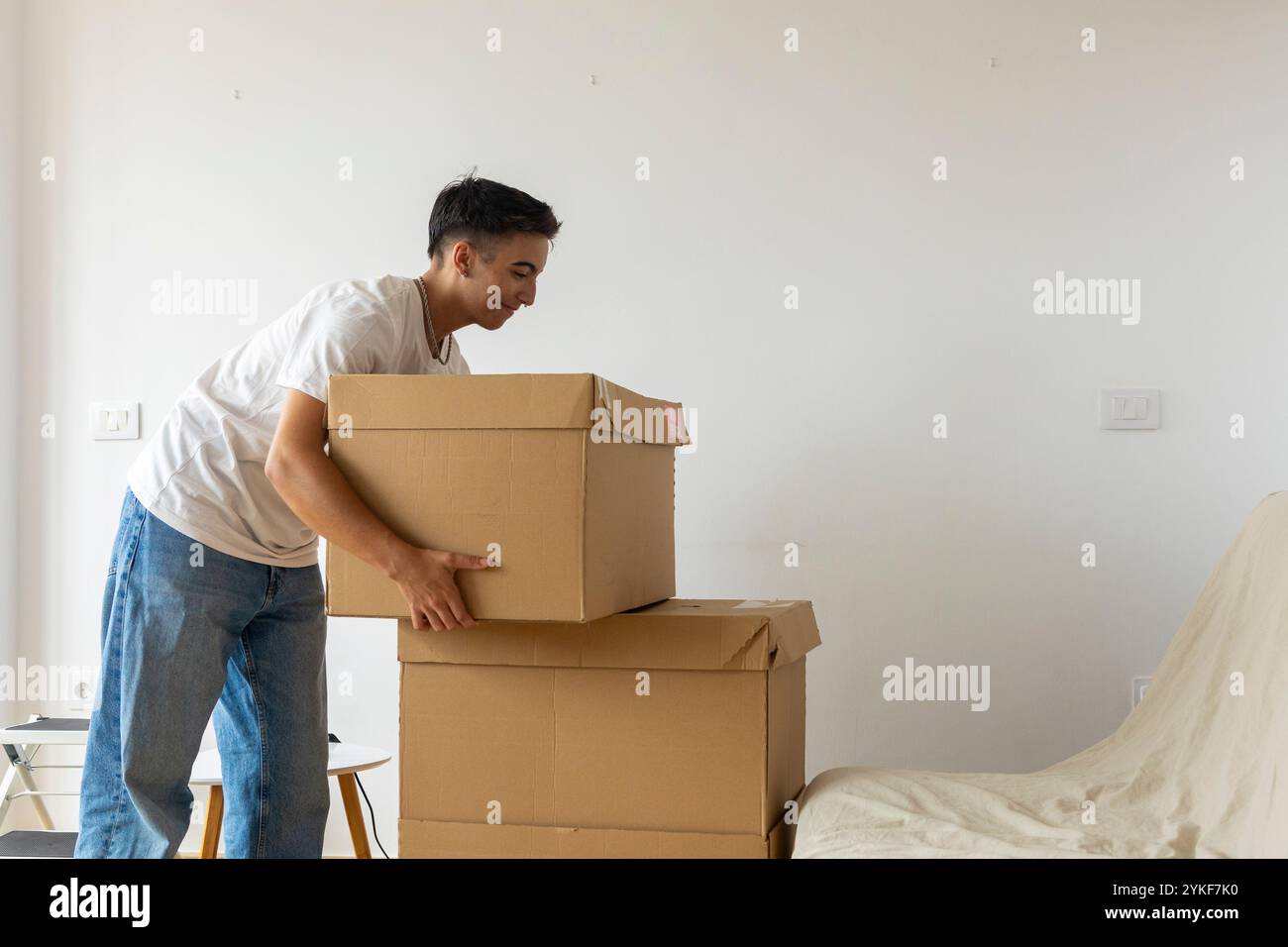 A joyful trans man is engaged in moving, stacking cardboard boxes in a ...