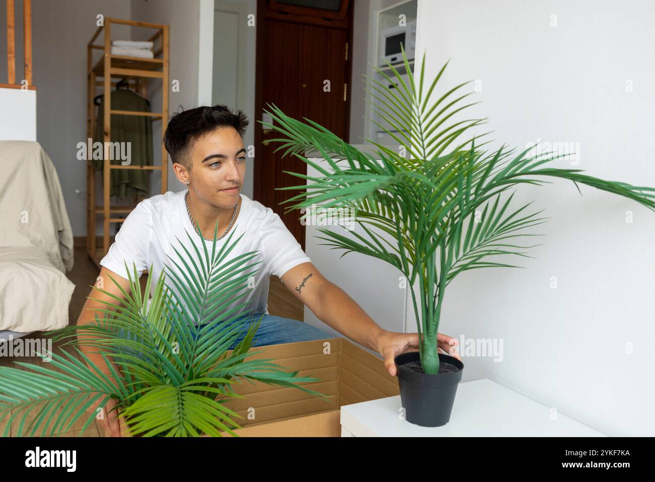A confident trans man happily rearranges potted plants while settling ...