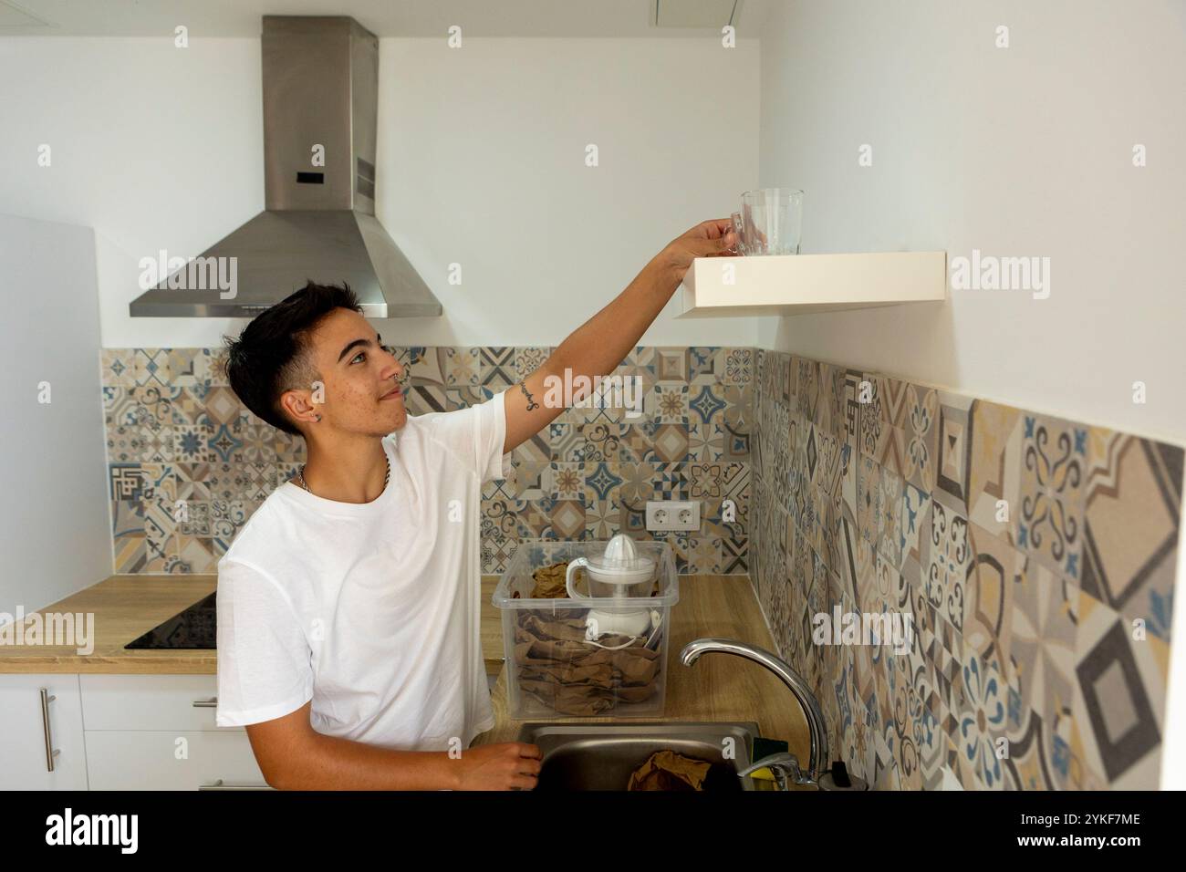 A trans man unpacks and arranges glassware in his well-lit, stylishly ...