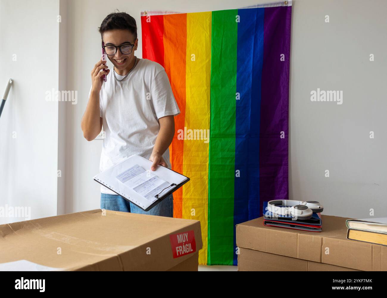 A cheerful trans man talks on the phone while organizing documents ...