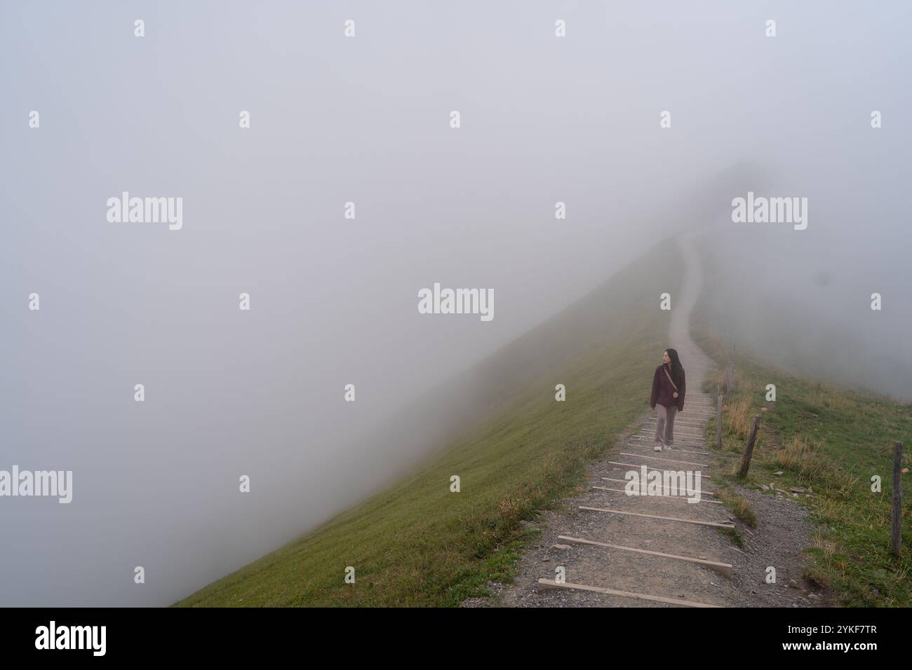 A lone individual walks a mist-covered path in Stoos, Switzerland ...