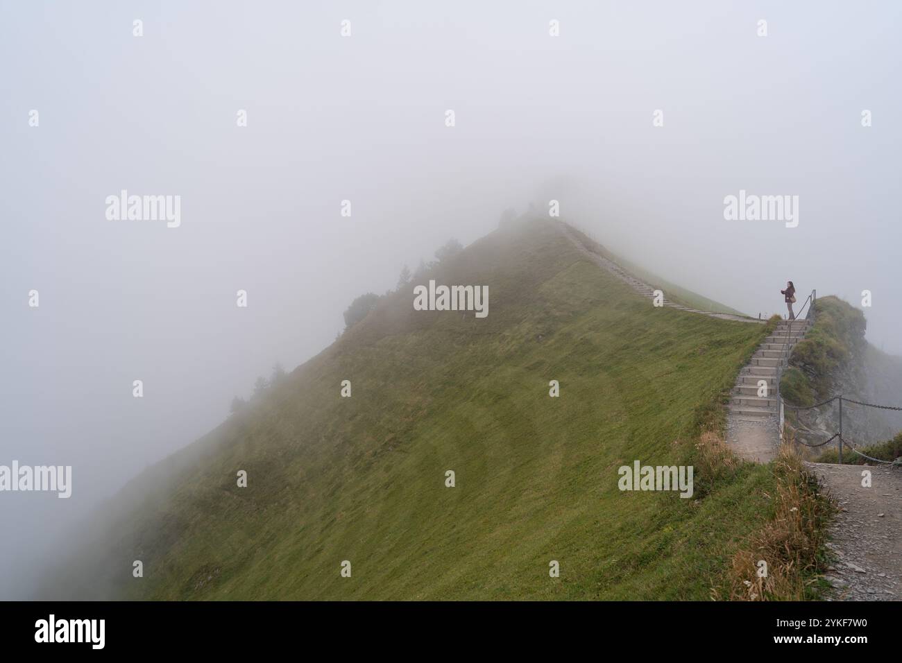 An Asian woman explores a mist-shrouded mountain trail in Stoos ...