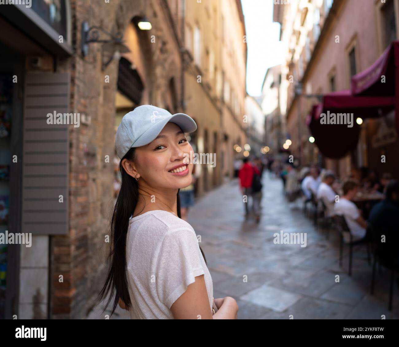An asian woman smiles while walking through the picturesque cobblestone ...