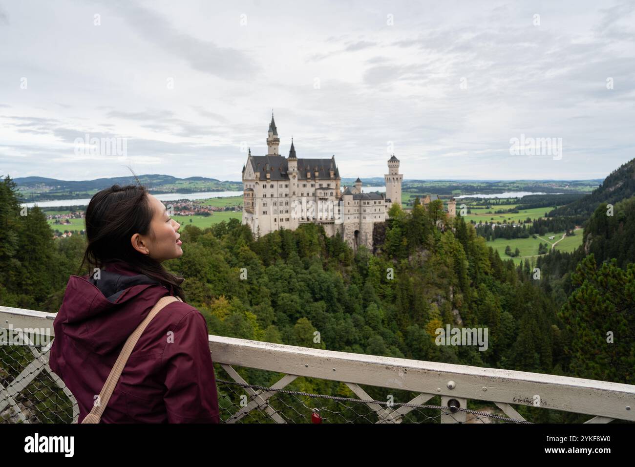 A woman admires the iconic Neuschwanstein Castle in Germany, surrounded ...