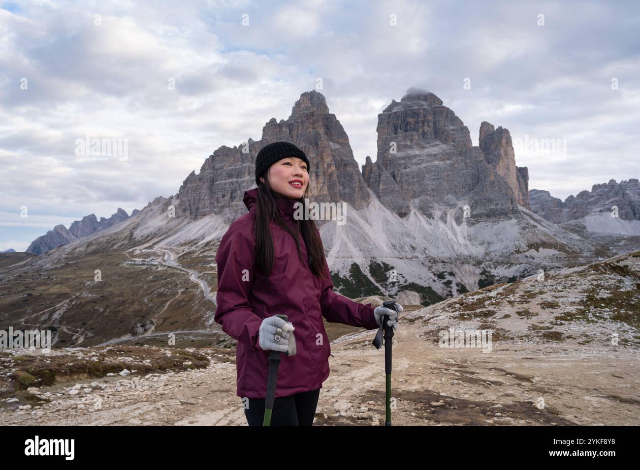 An asian woman in a maroon jacket enjoys a hike near Tre Cime di ...